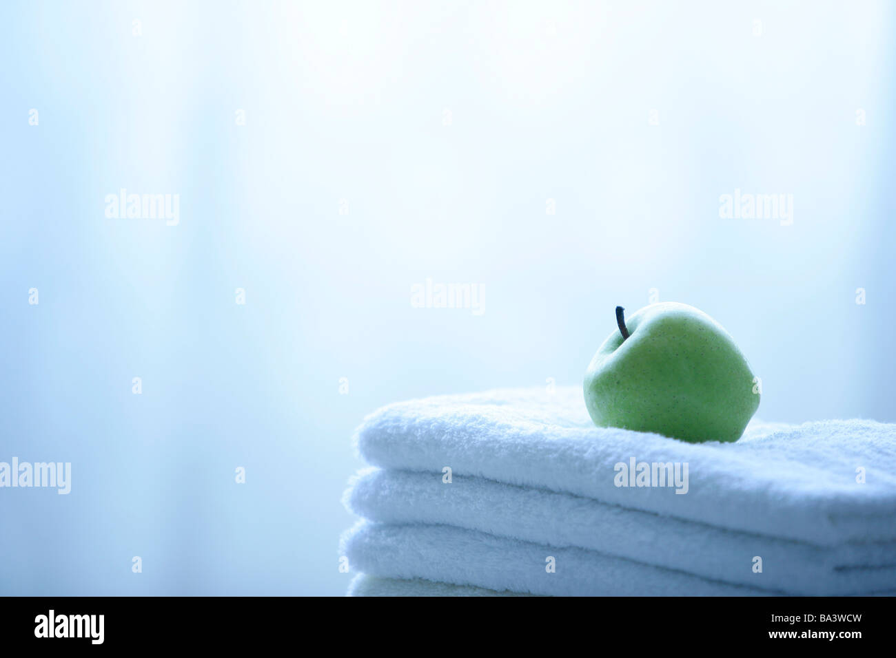 Green apple on stack of folded towels Stock Photo - Alamy