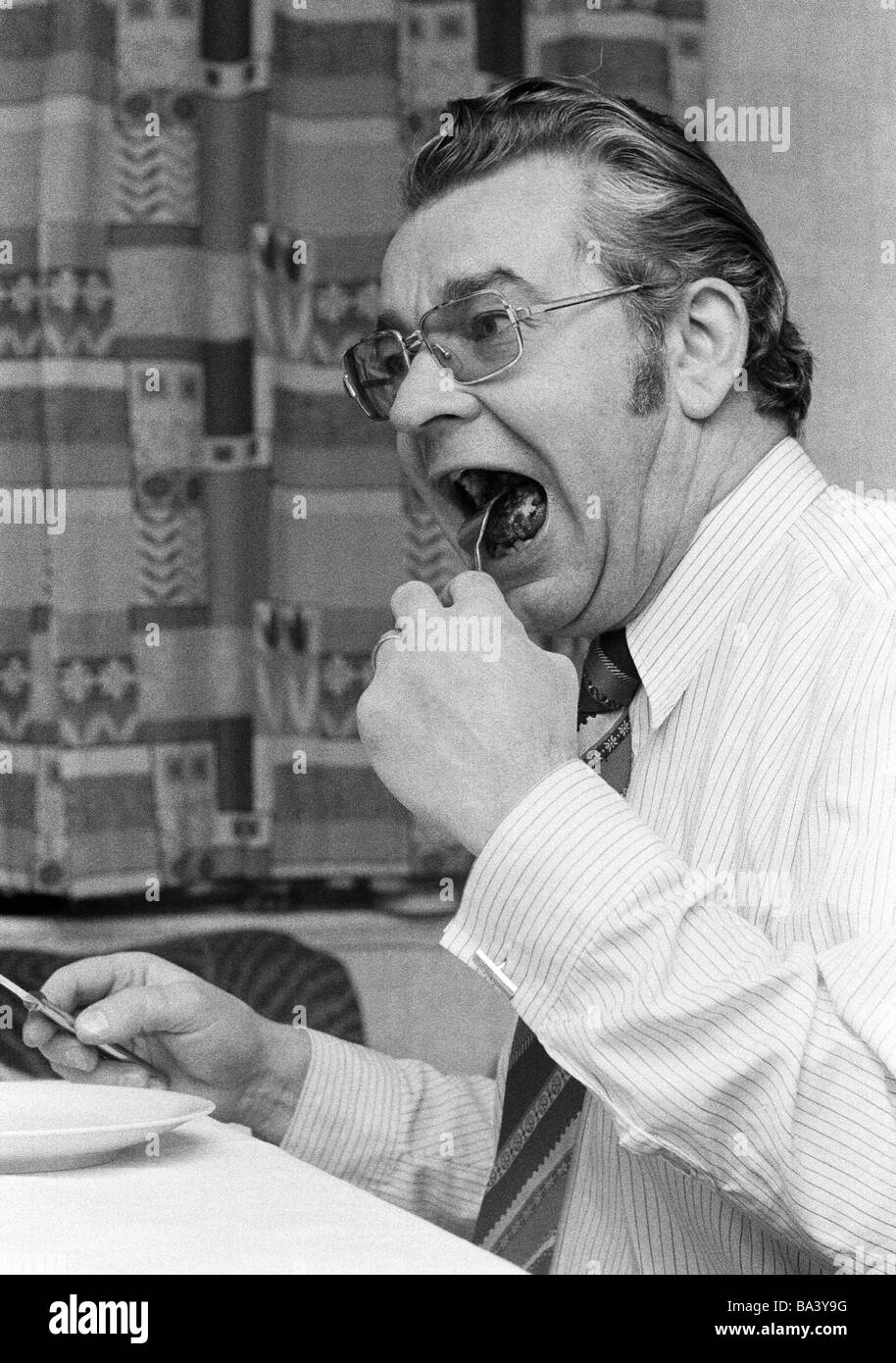 Seventies, black and white photo, people, man eating using forks and ...