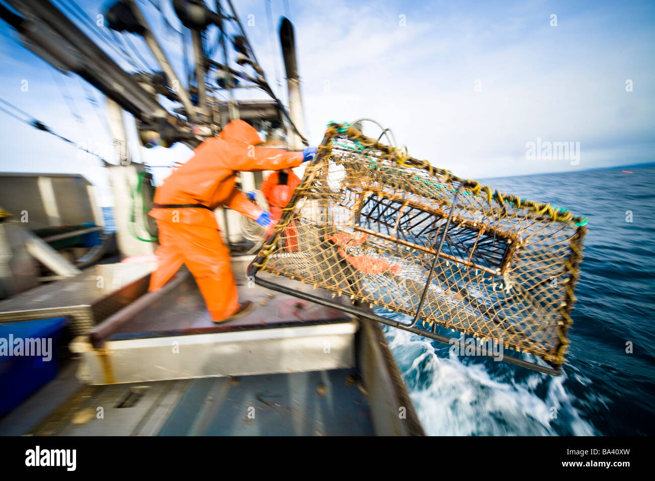 Deckhands lower a baited pot over the deck of the F/V Centurion while ...