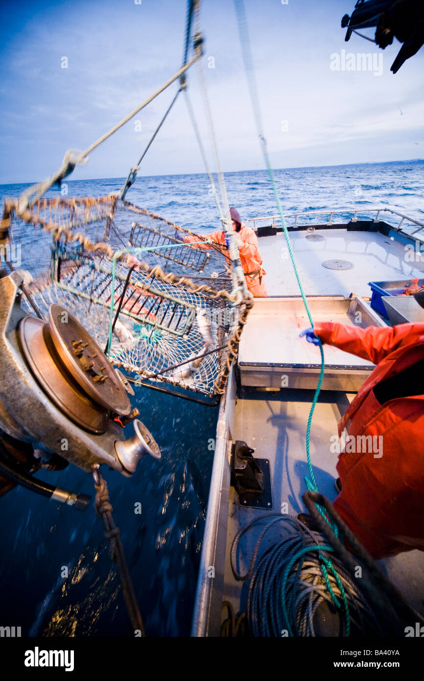 Deckhands lower a baited pot over the deck of the F/V Centurion while ...