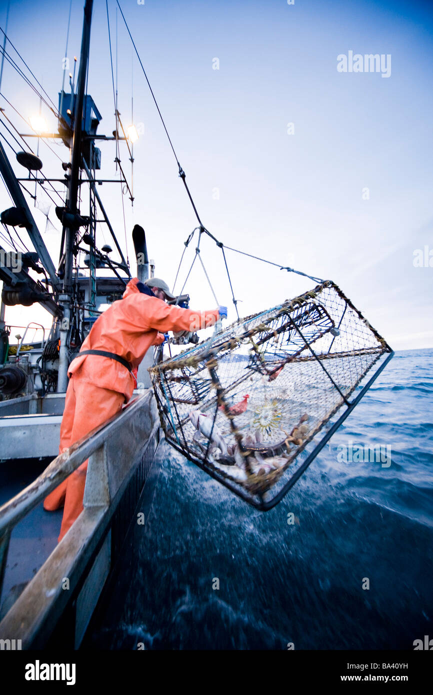 Deckhands lower a baited pot over the deck of the F/V Centurion while ...