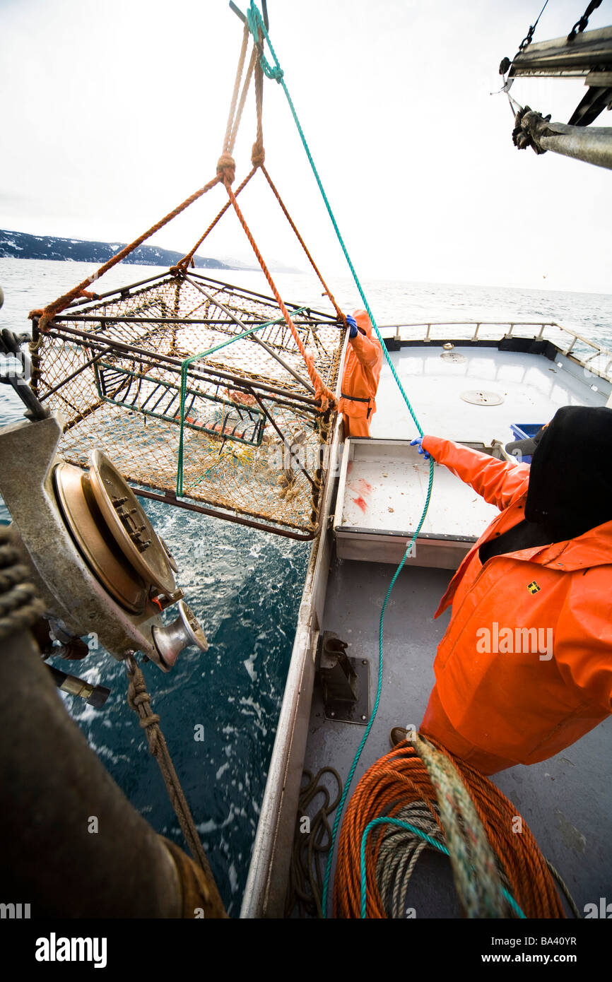 Deckhands lower a baited pot over the deck of the F/V Centurion while ...