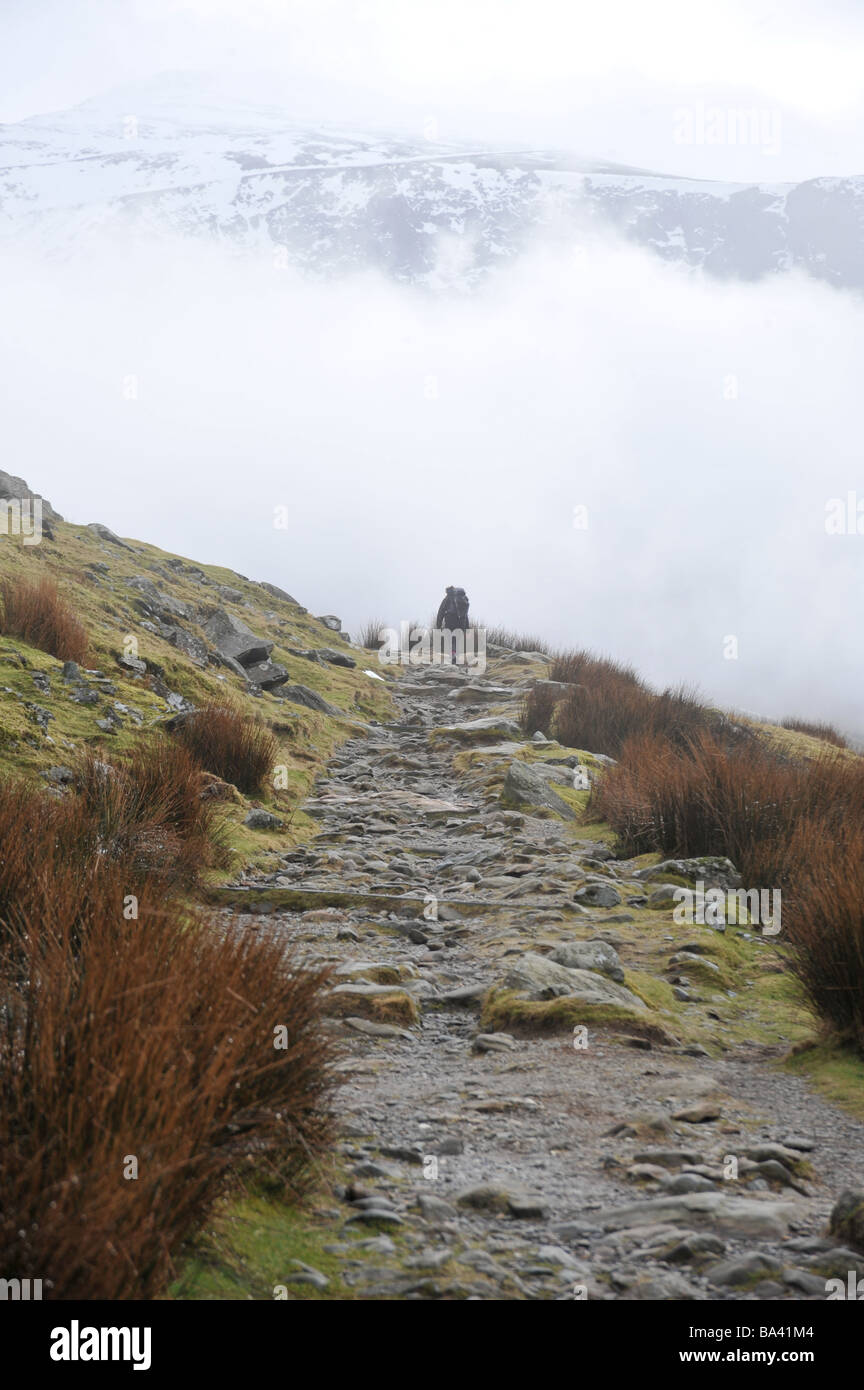 Lone walker ascends the Llanberris path on Mount Snowdon, climbing into ...