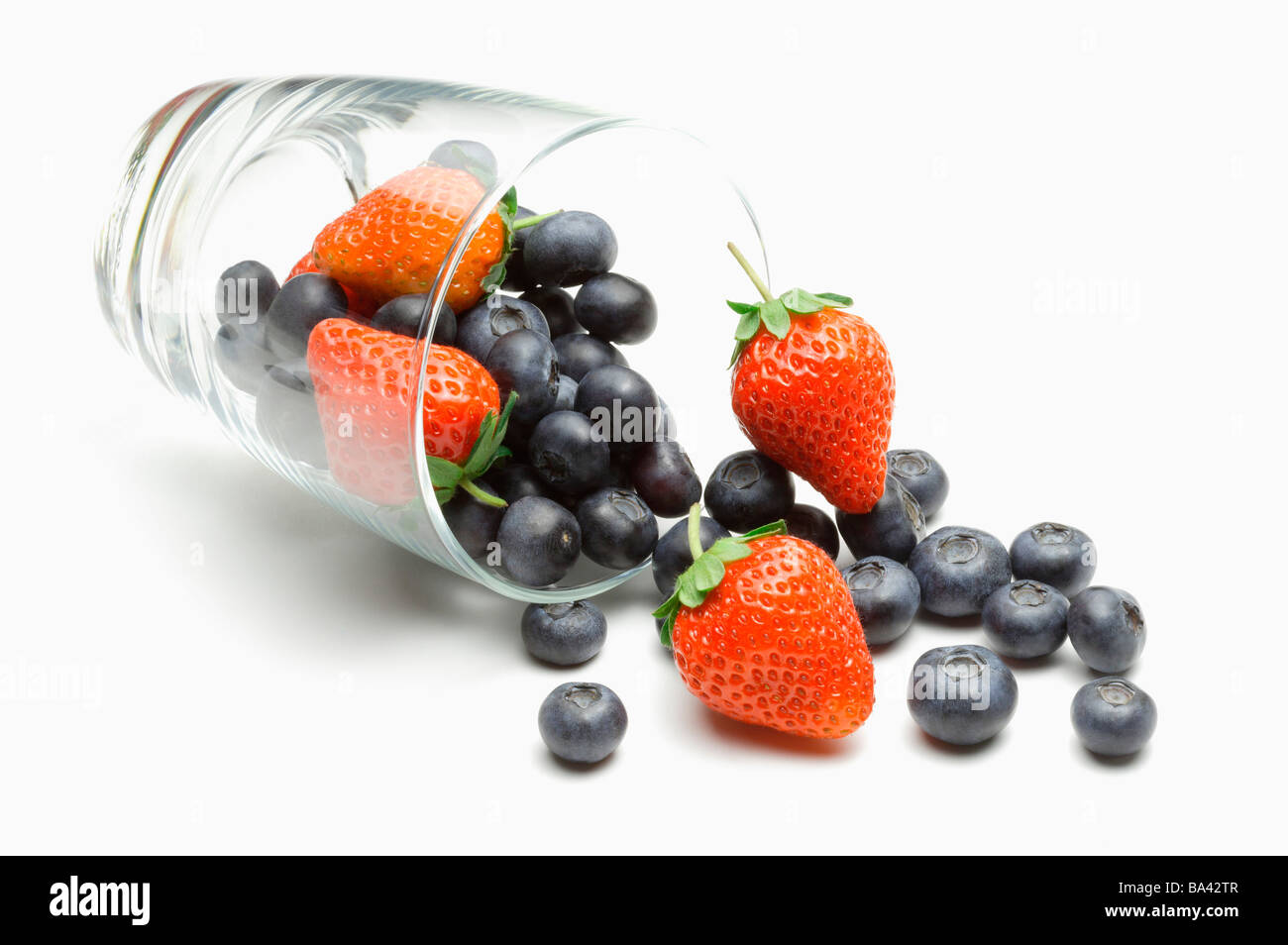 Glass of spilled blueberries and strawberries Stock Photo - Alamy