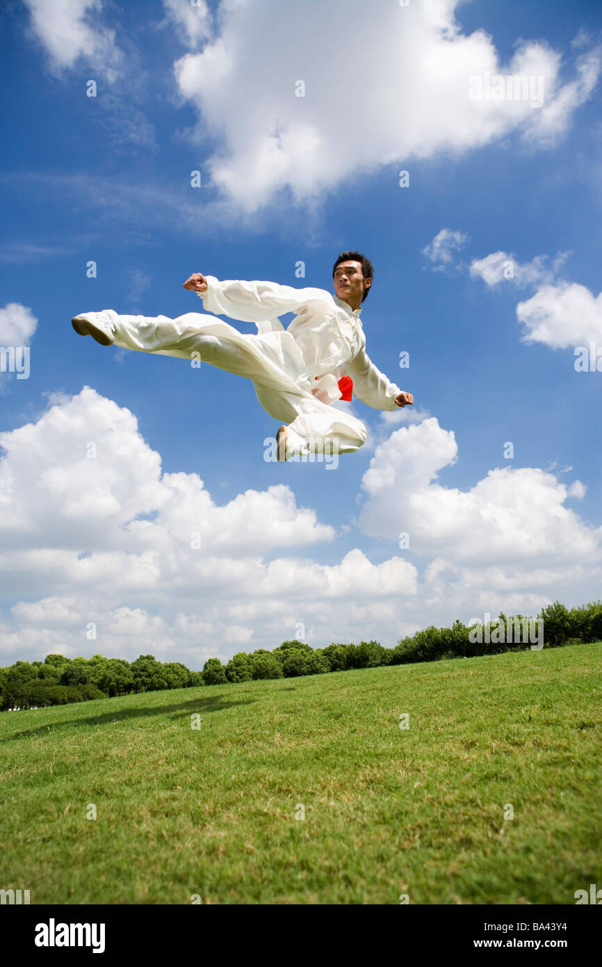 Young man in martial arts uniform kicking leg in mid air Stock Photo ...