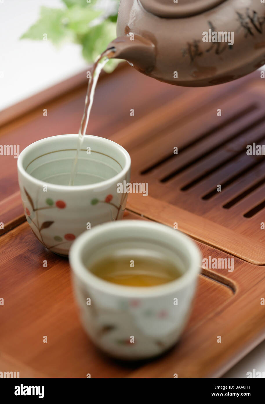 Tea being poured into tea cup on tray high angle view Stock Photo - Alamy
