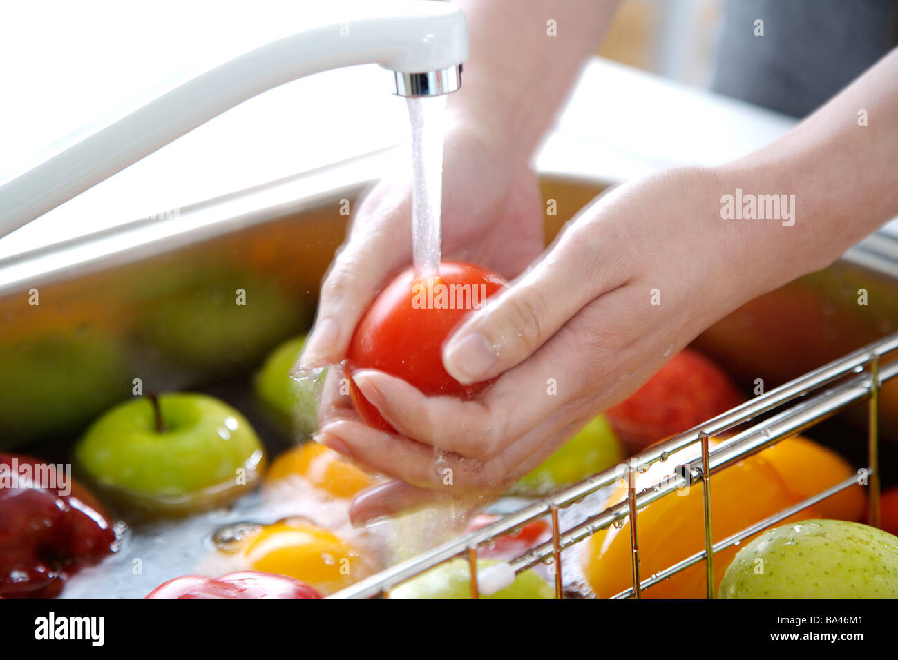 Young woman washing apples under tap close up Stock Photo - Alamy