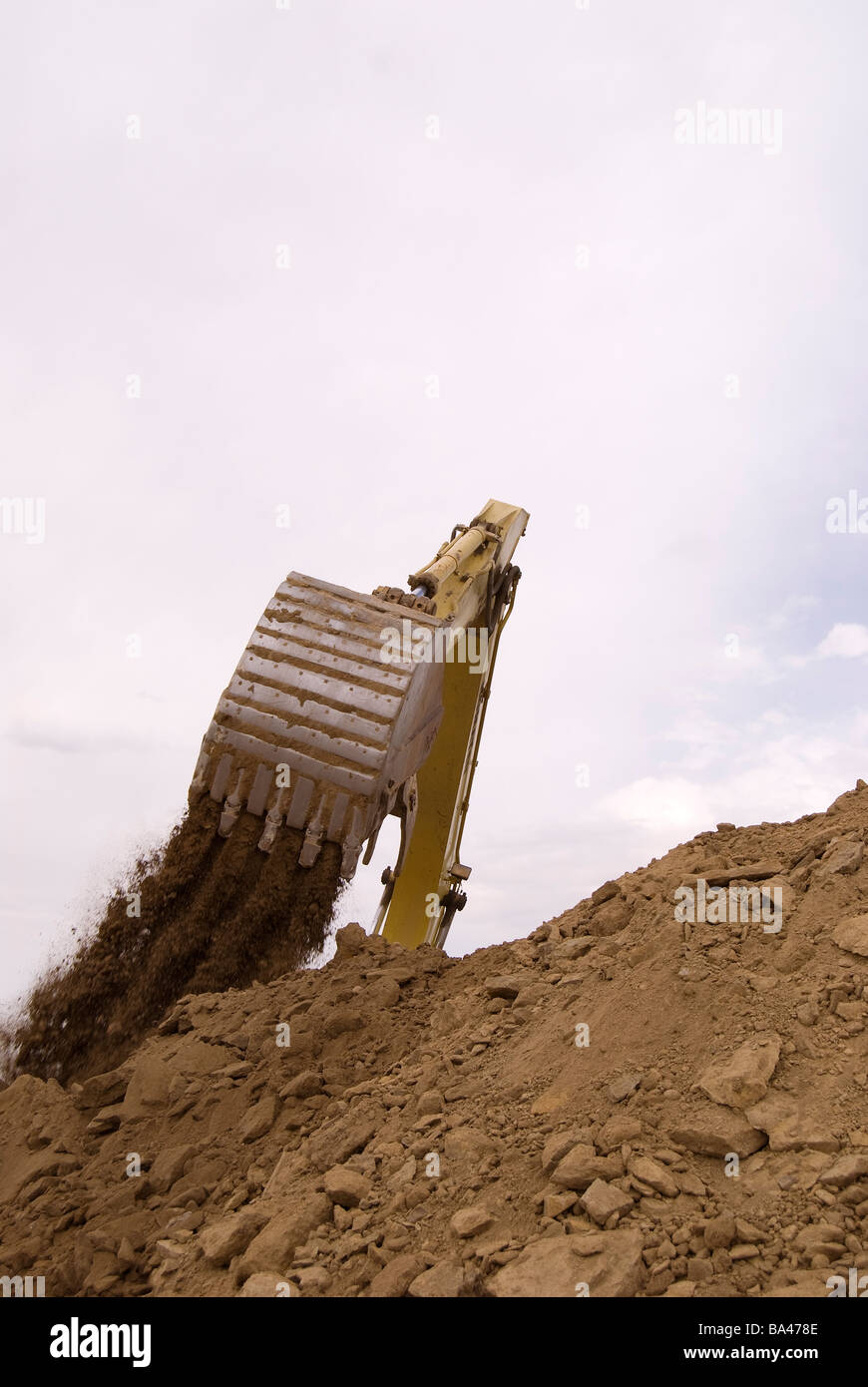 Excavator bucket dumping soil and rock onto stockpile Stock Photo - Alamy