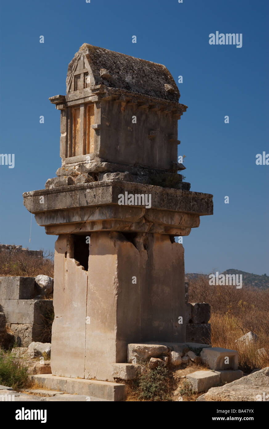 An ancient stone sarcophagus sits atop a limestone pillar in the ruins ...