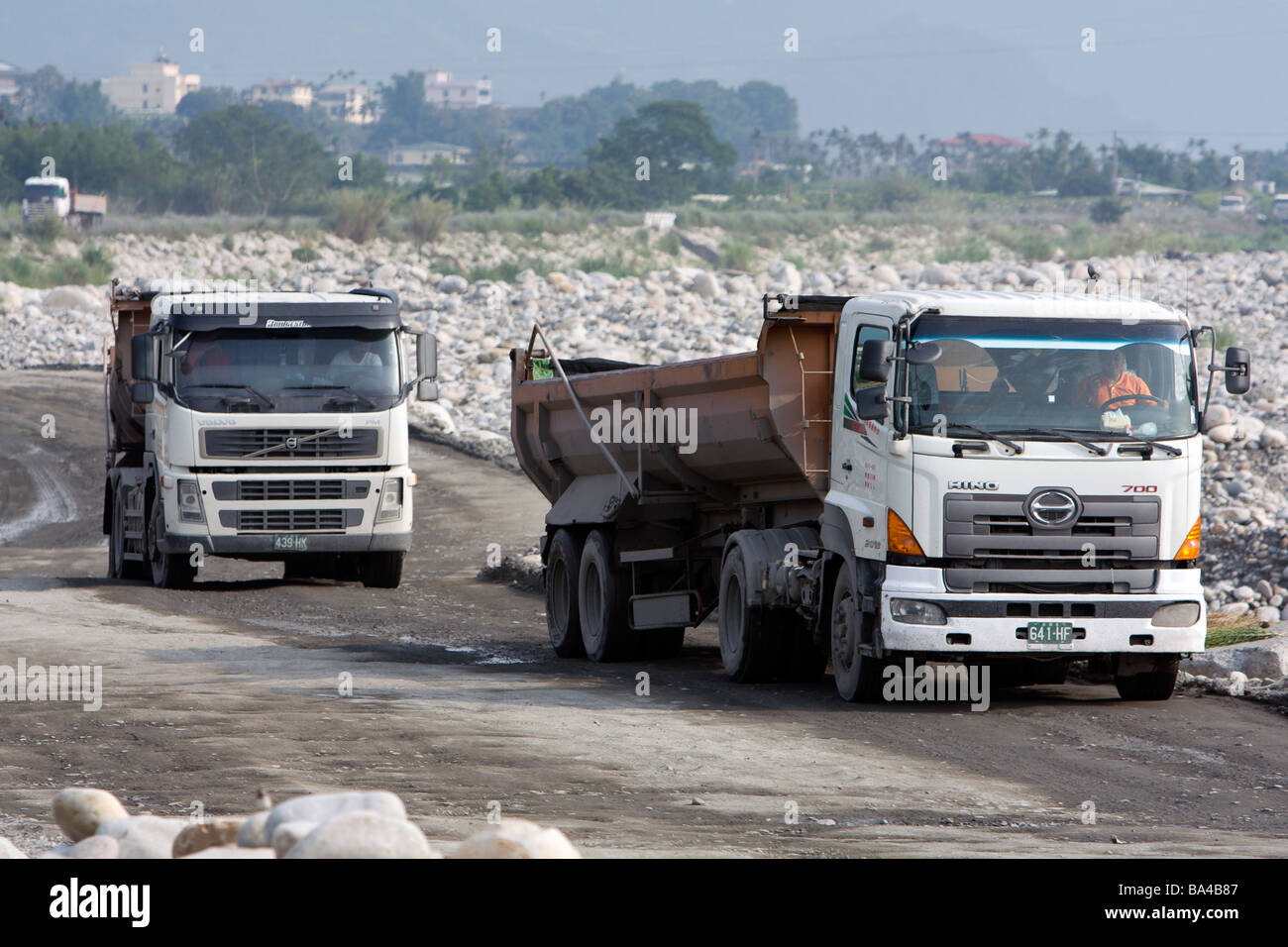Dump trucks driving into a busy rock quarry, stony terrain, Dajia River ...