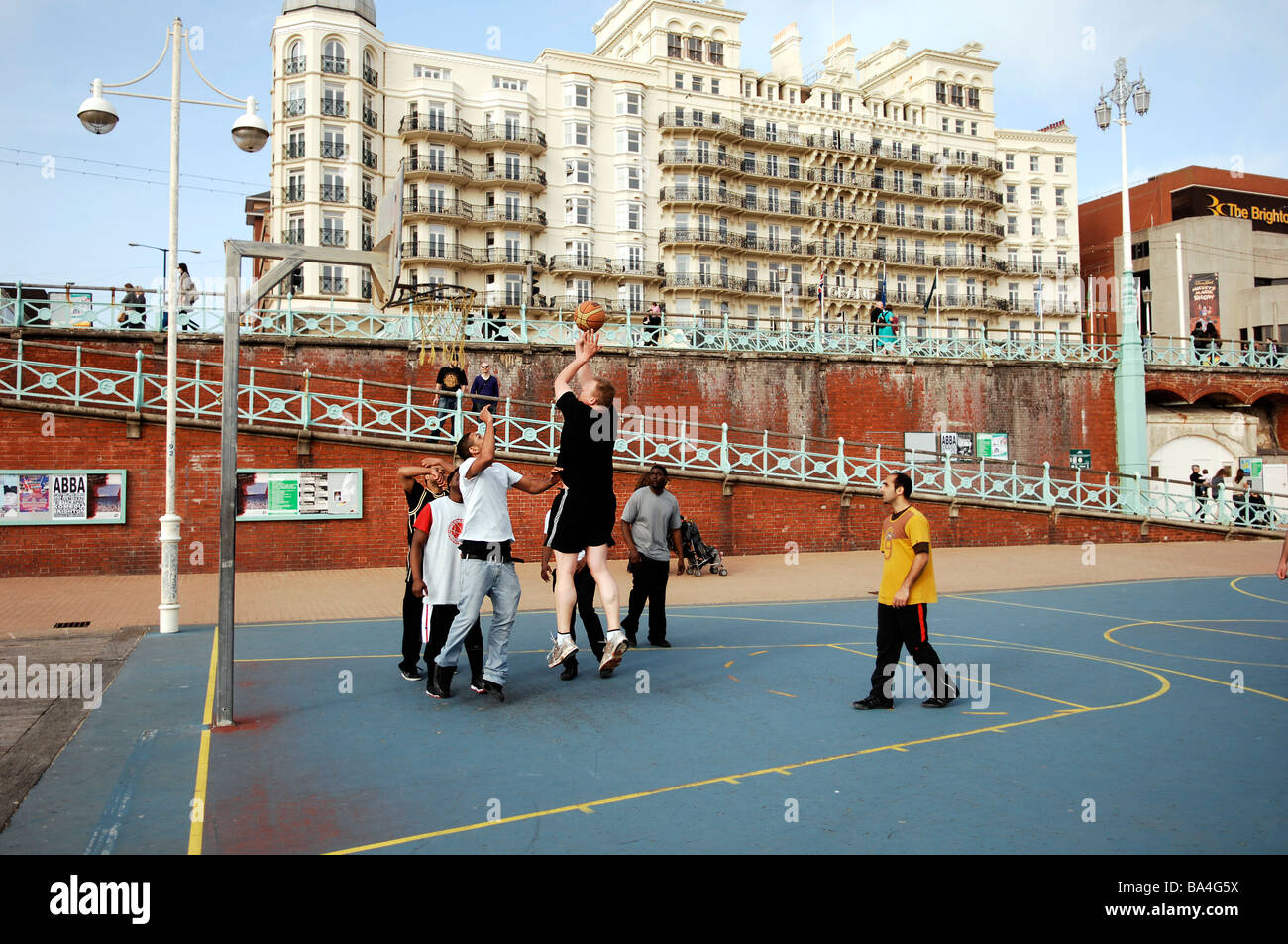 Basketball players in action on the outside seafront court along ...