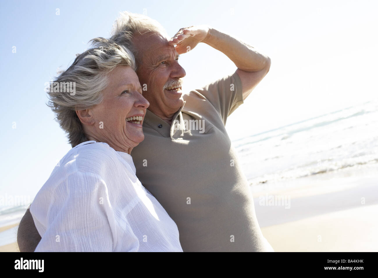 Sandy beach senior-pair arm in arm walk laughs cheerfully portrait ...