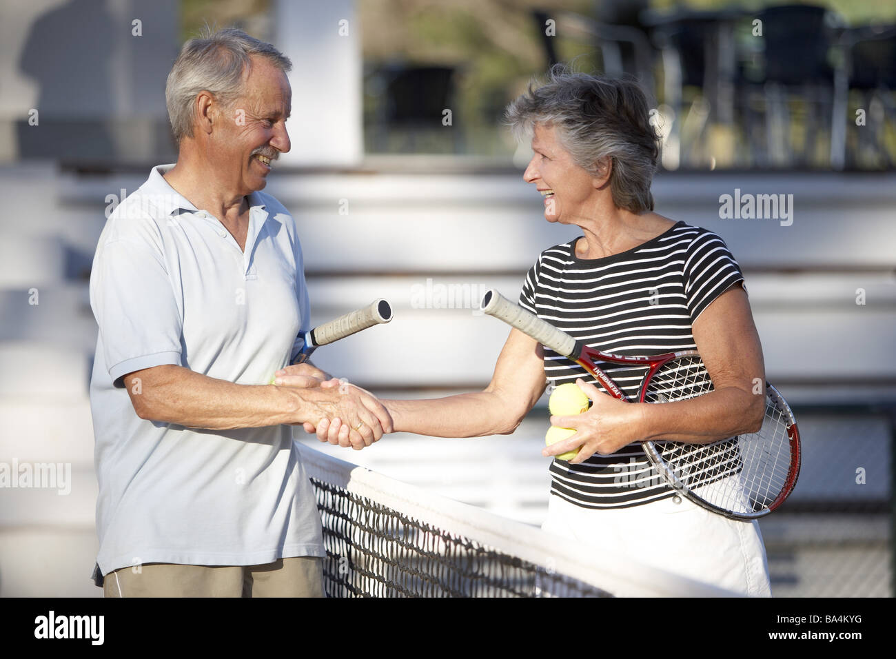 Tennis court senior-pair net gaze-contact smiles handshake series ...