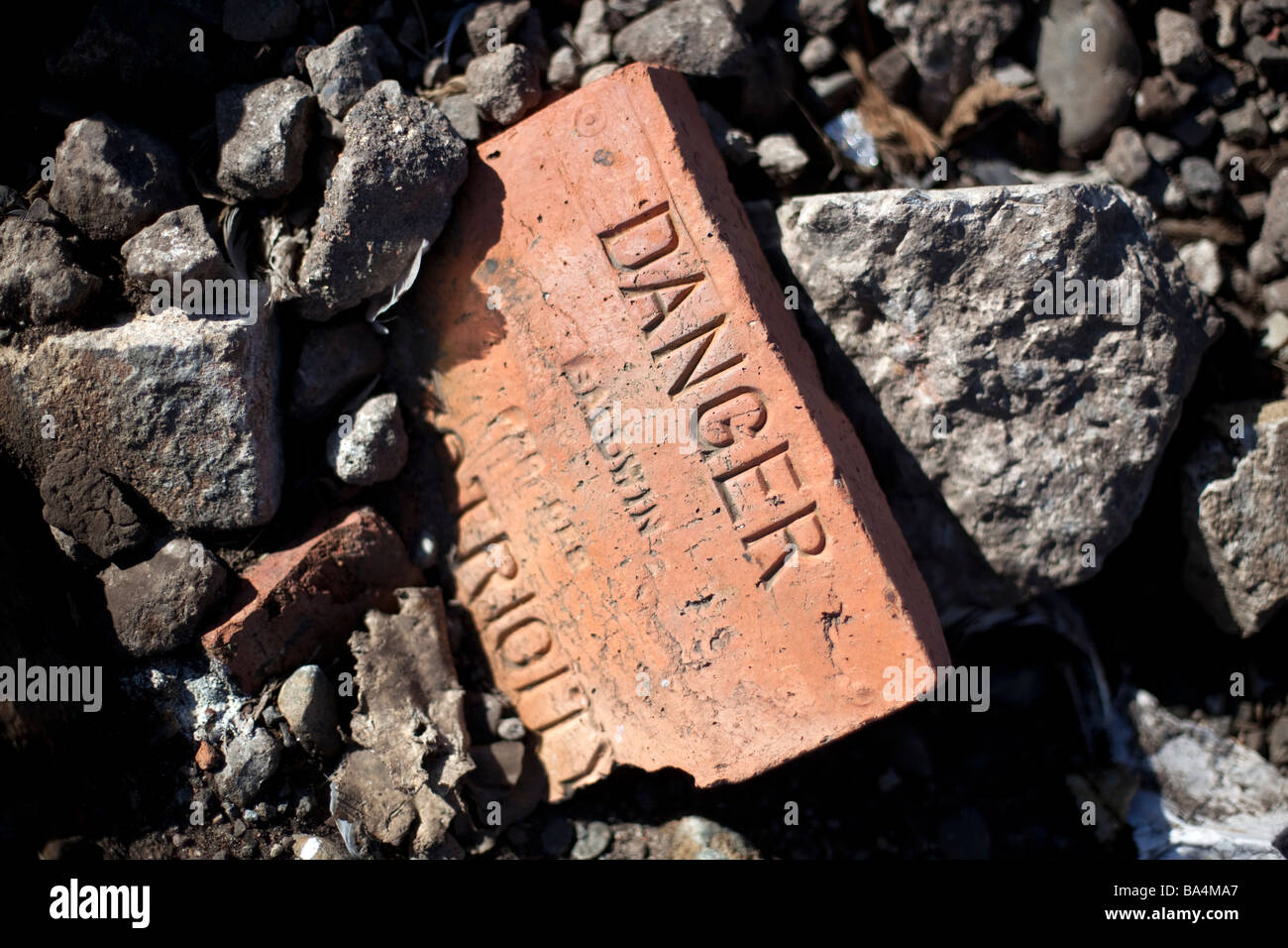 A danger warning sign carved into a brick in building rubble on a ...