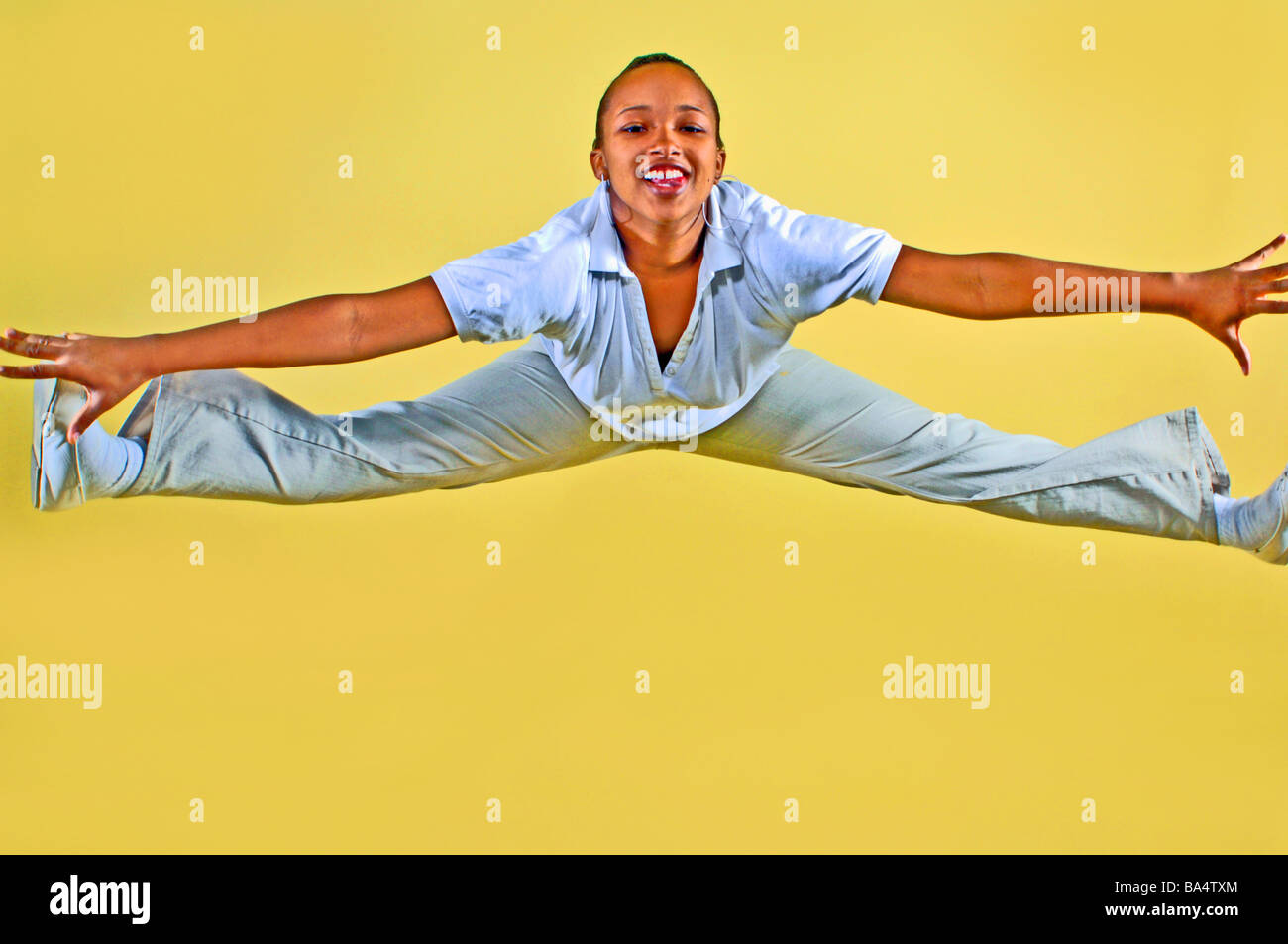 Athletic excited, ethnic female jumps in the air doing the splits and ...