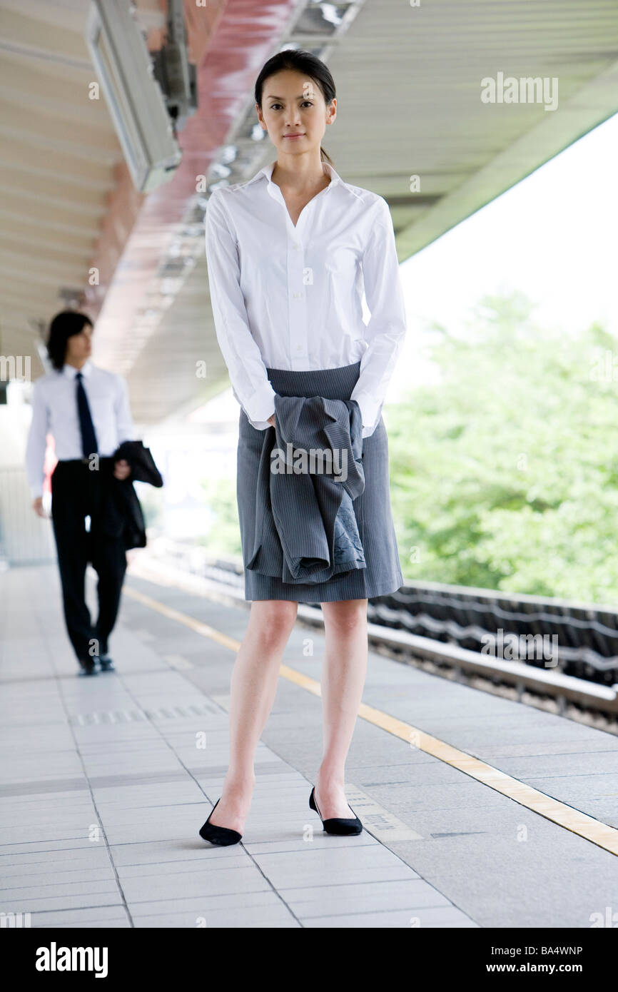 Businesswoman standing on train platform looking at camera businessman ...
