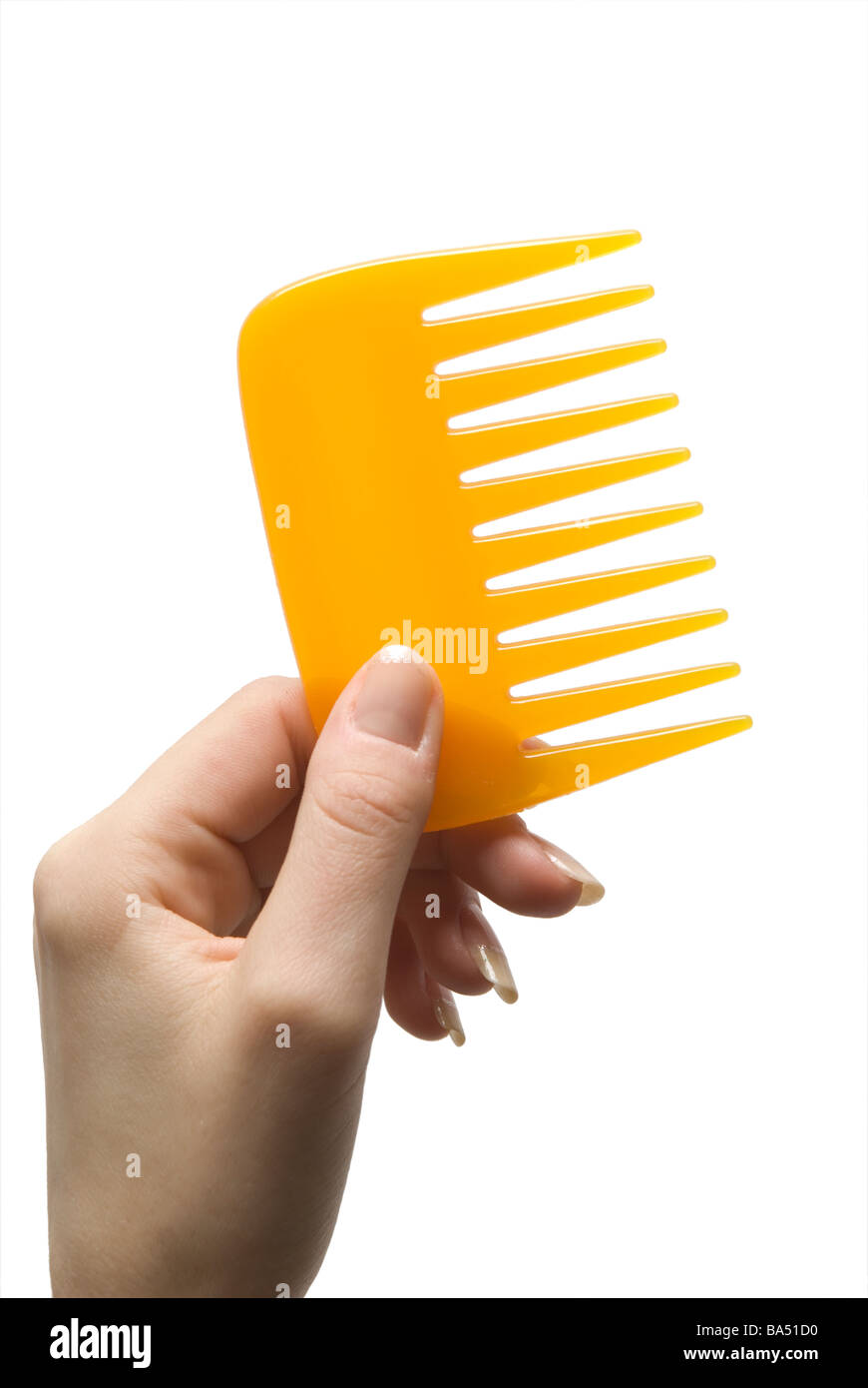 Hand holding a plastic yellow comb against a white background Stock ...