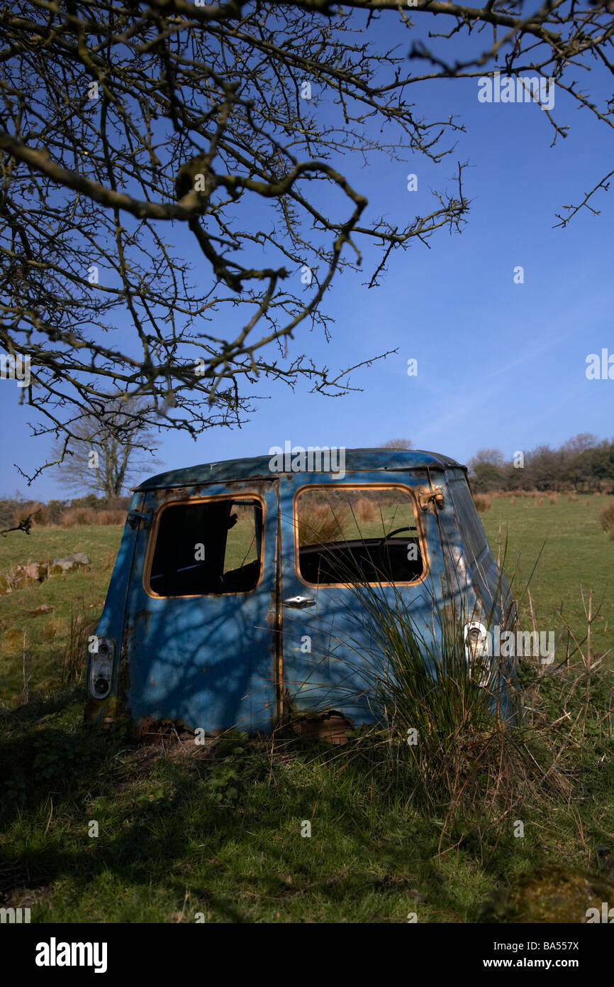old blue rusted abandoned wreck of an old mini van in a field in county ...
