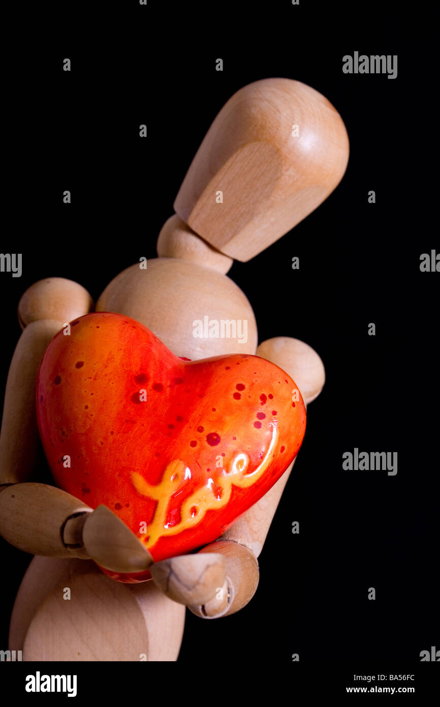Wooden artist's figure holding heart-shaped object Stock Photo - Alamy