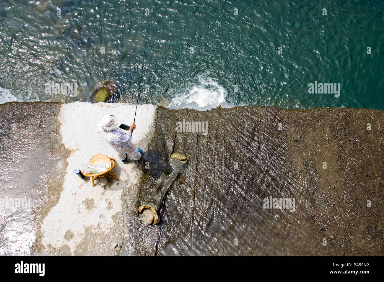 Fisherman at weir edge, low head dam, aerial view of man fishing next ...