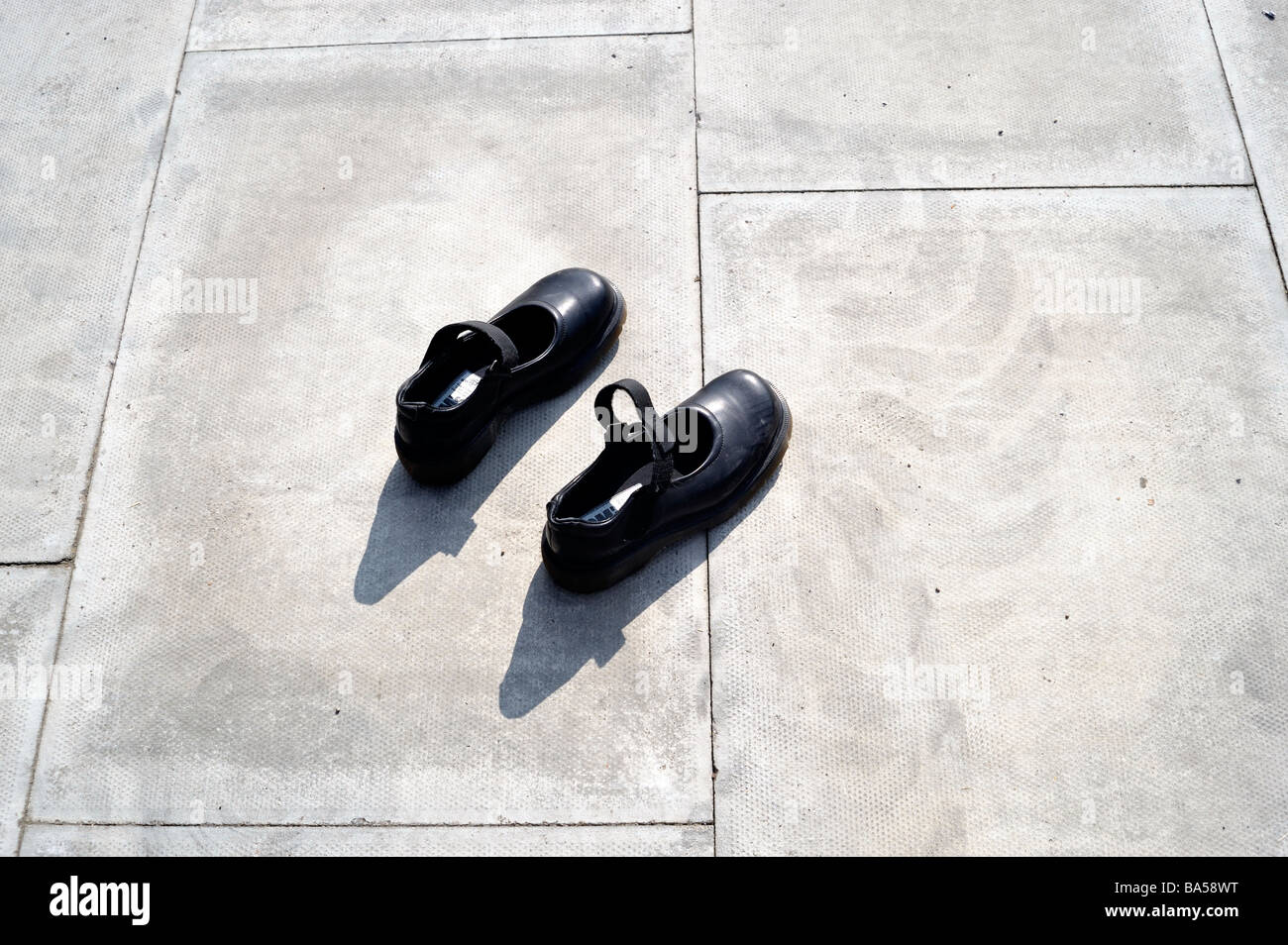 Shoes on concrete paving slabs next to tyre track Stock Photo - Alamy