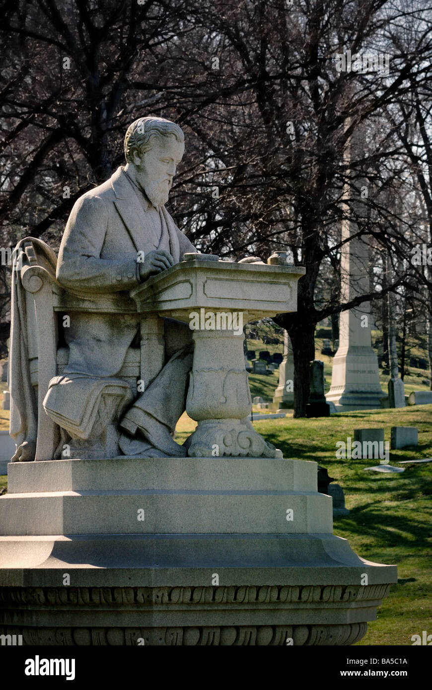 A large statue of a man seated at a desk is a monument on an old grave ...