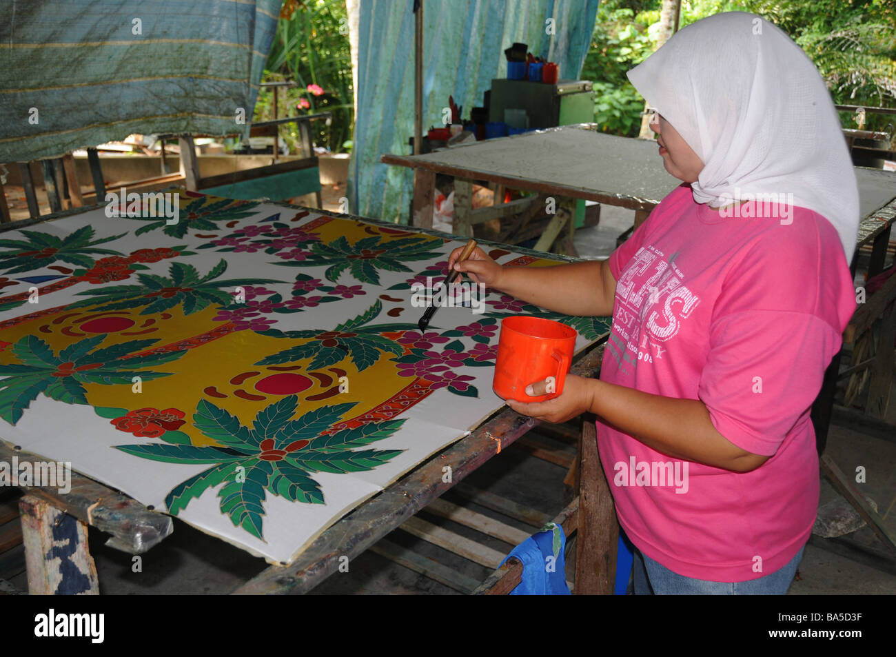 A workers painting traditional patterns at a batik factory on the ...