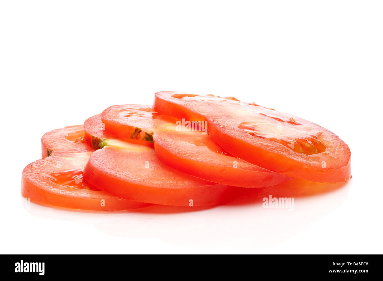 A horizontal close up of a stack of 4 slices of fresh tomato on white ...