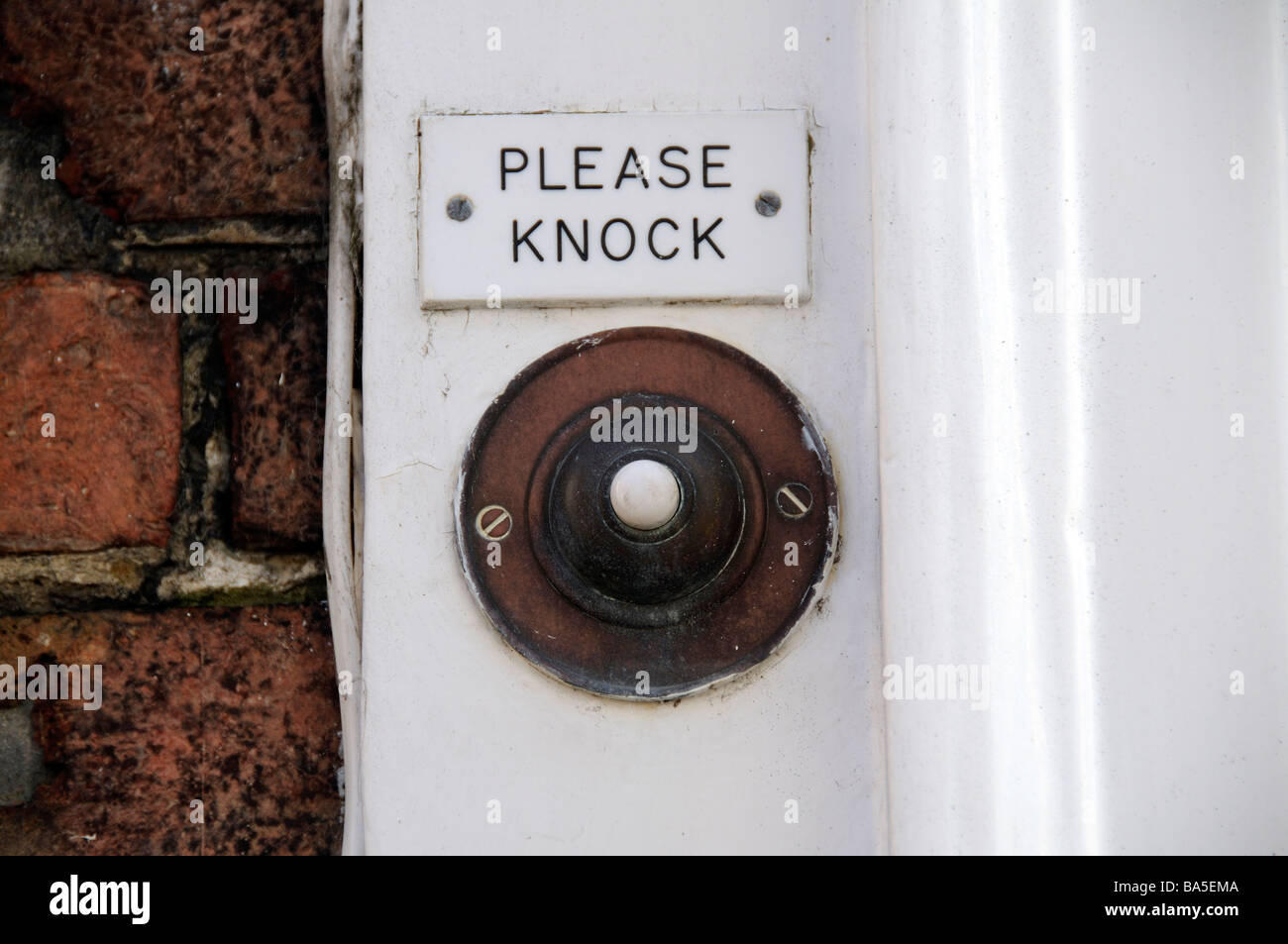 Bell push on doorway with sign saying please knock Stock Photo - Alamy