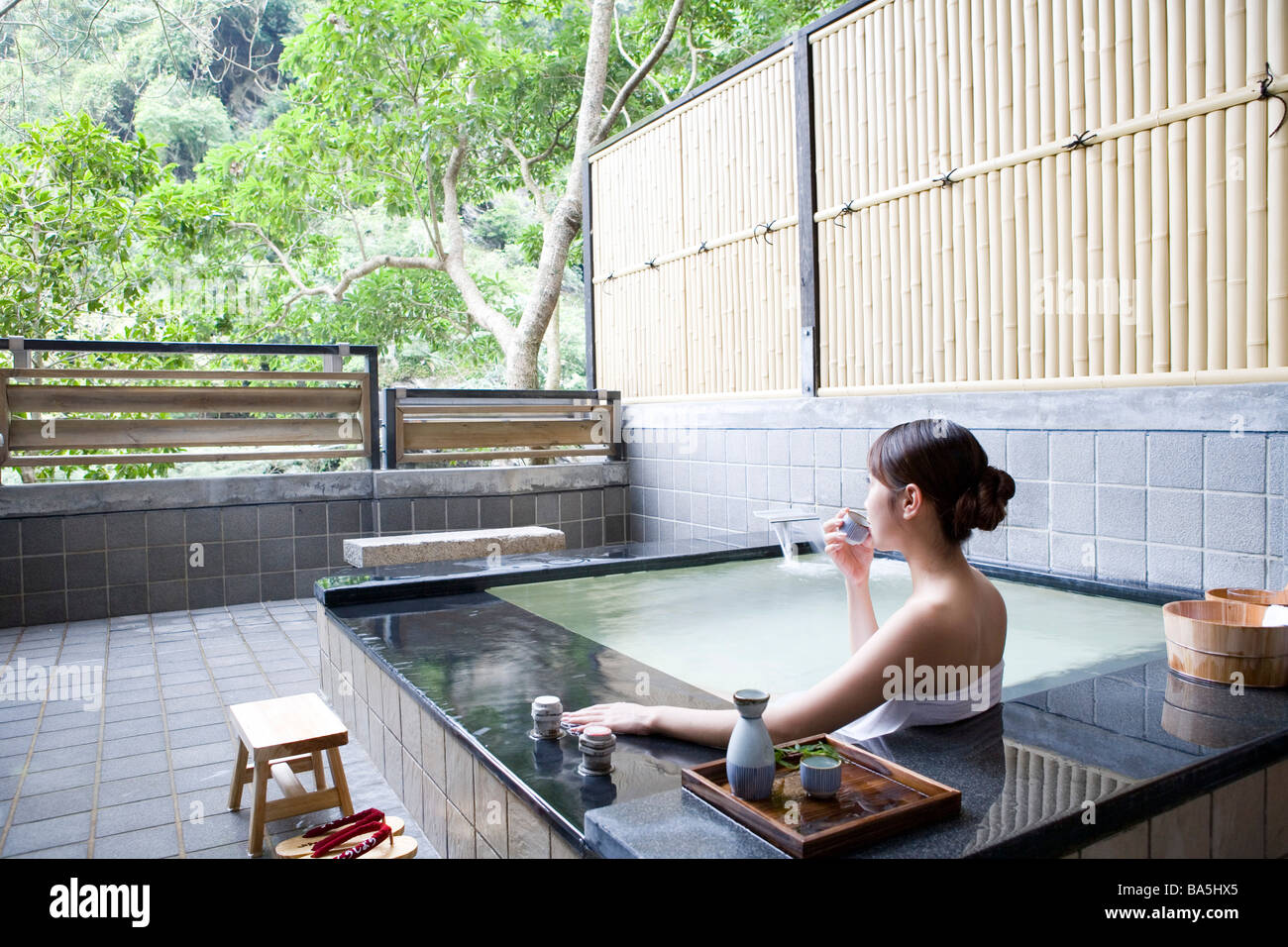 Young woman in bath towel soaking in pool drinking sake rear view Stock ...
