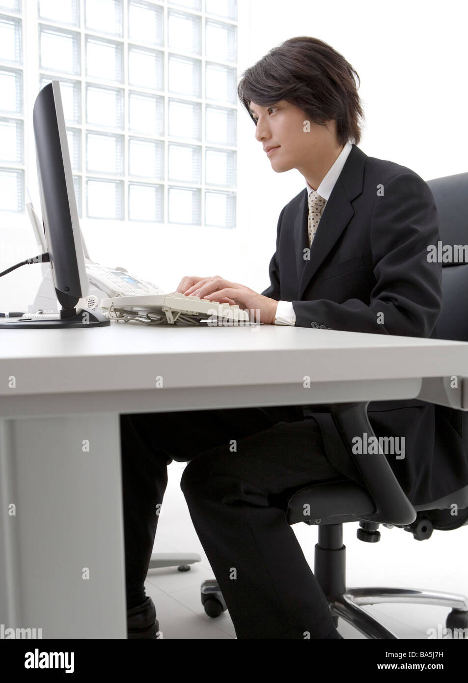 Businessman sitting at desk using computer side view Stock Photo - Alamy