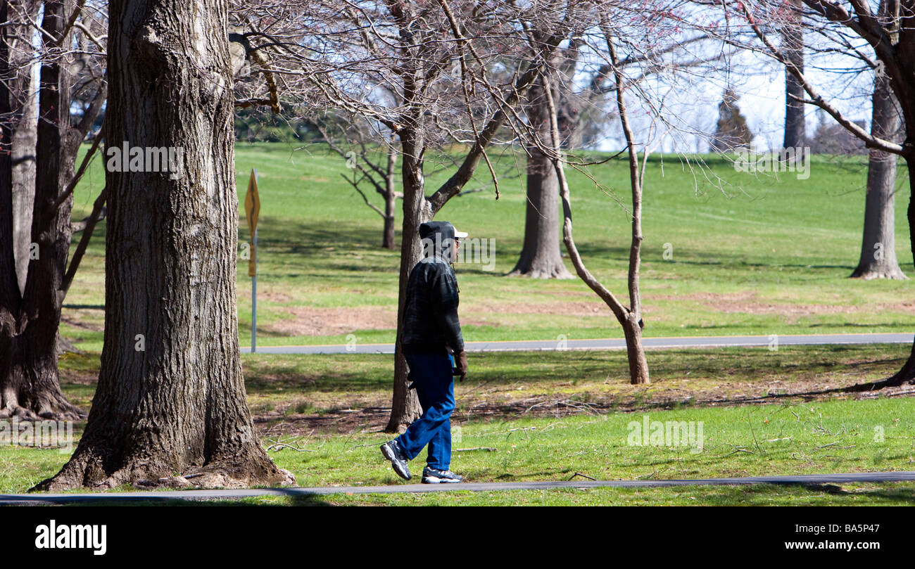 A man taking a walk on a paved path in a well groomed park Stock Photo ...