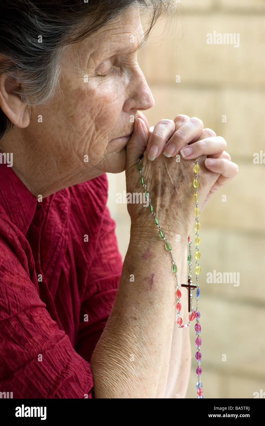 An older woman praying with her rosary Stock Photo - Alamy