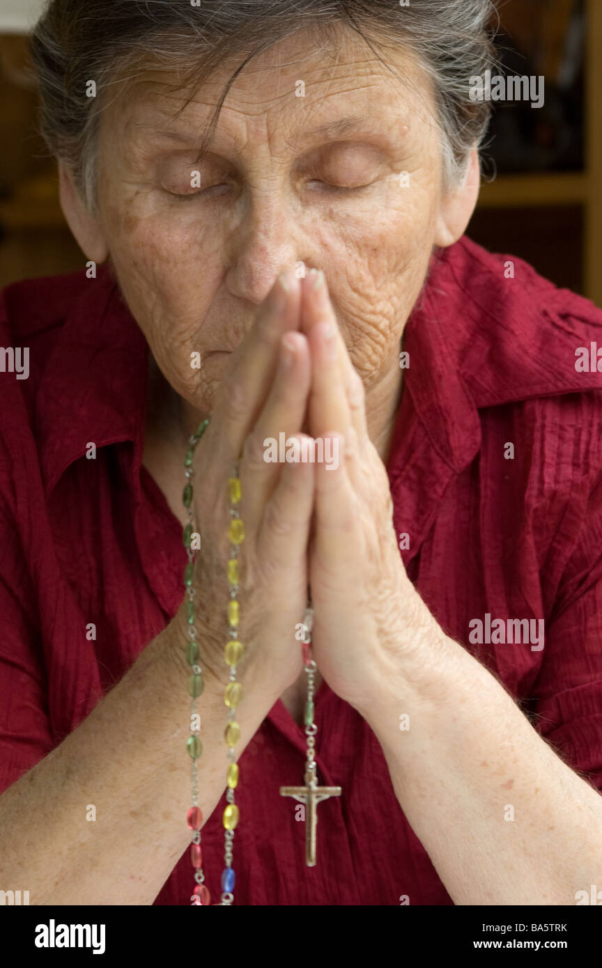 An older woman praying with her rosary Stock Photo - Alamy