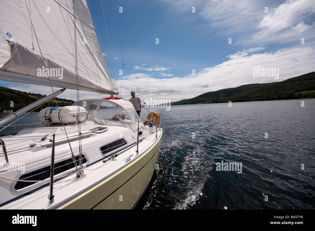 One man Sailing a small yacht in the Kyles of Bute in the Firth of ...
