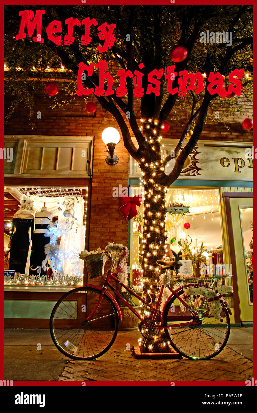 Brightly lit bicycle leaning against tree with Christmas decorations ...