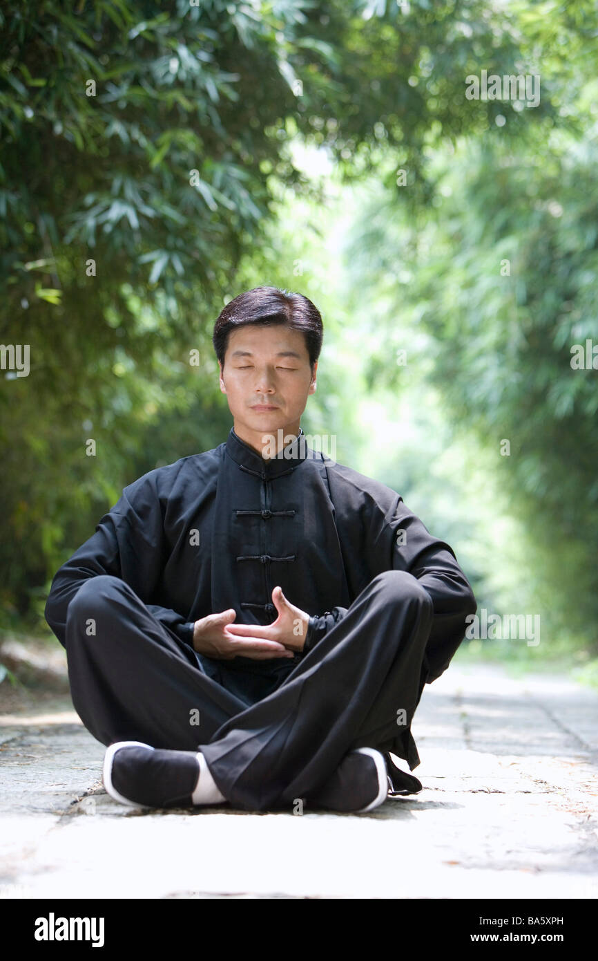 Mature man sitting on ground practicing Tai Chi Stock Photo - Alamy
