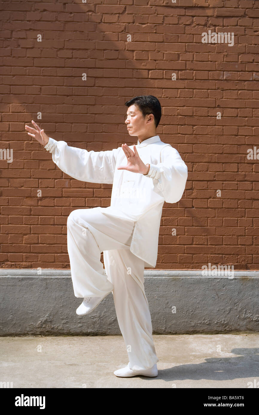 Man doing Tai Chi in front of surrounding wall Stock Photo - Alamy