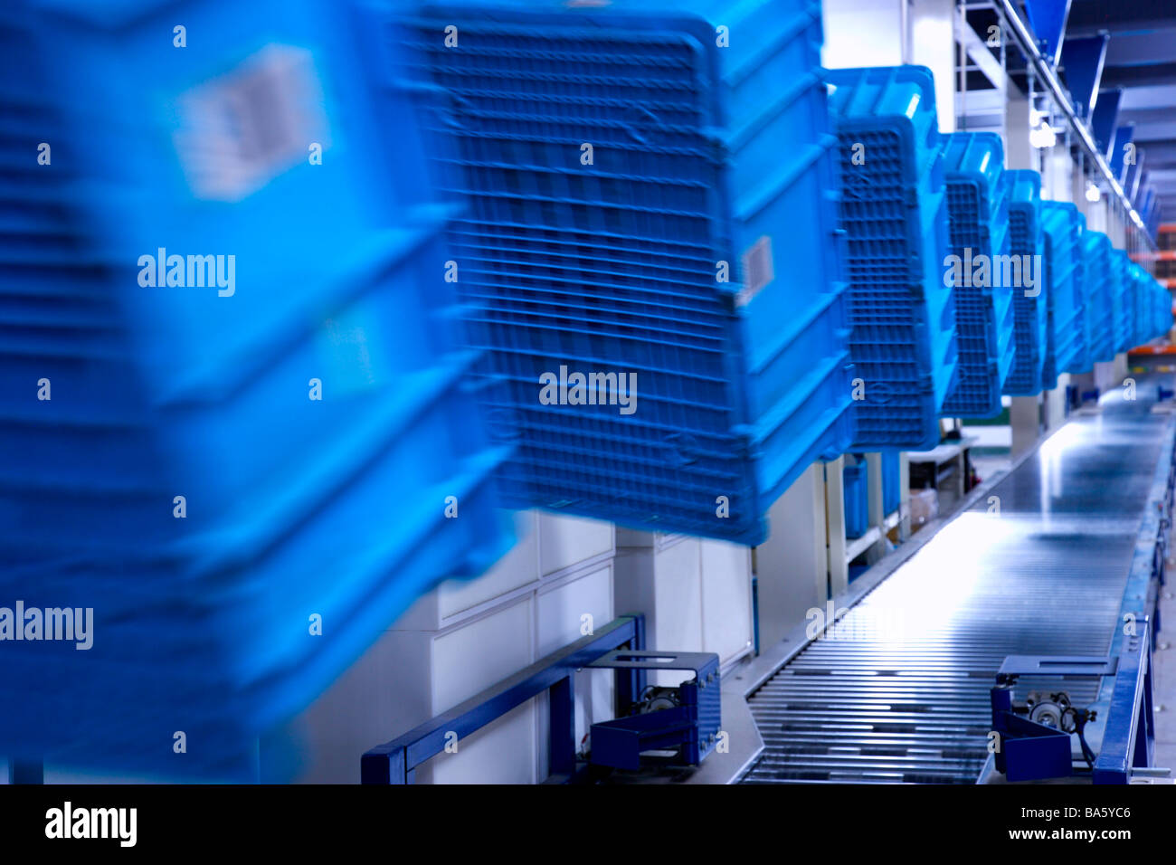 Blue plastic boxes hanging over conveyor belt Stock Photo - Alamy