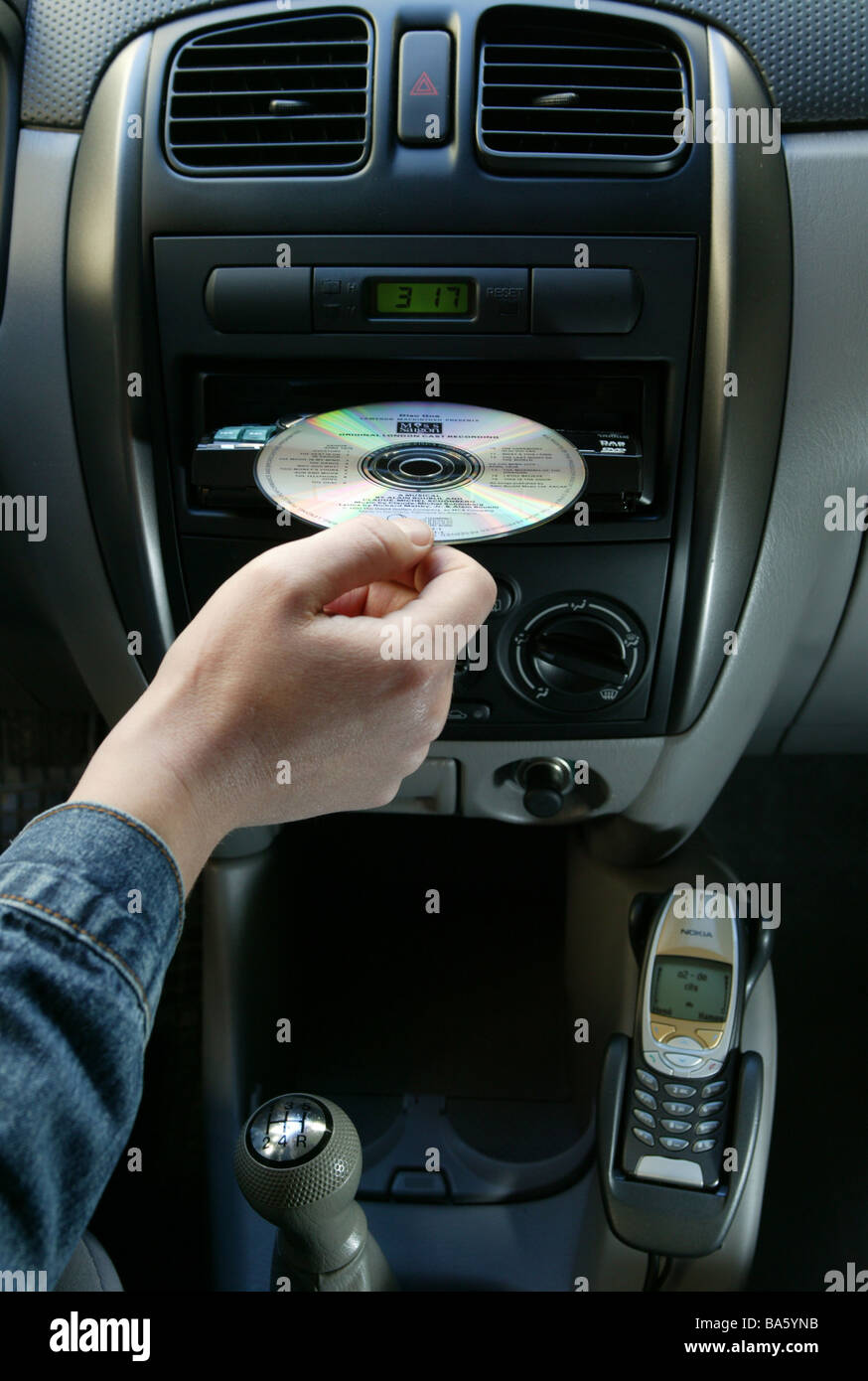 Car indoors woman hand CD CD players cell phone puts in mounting no ...