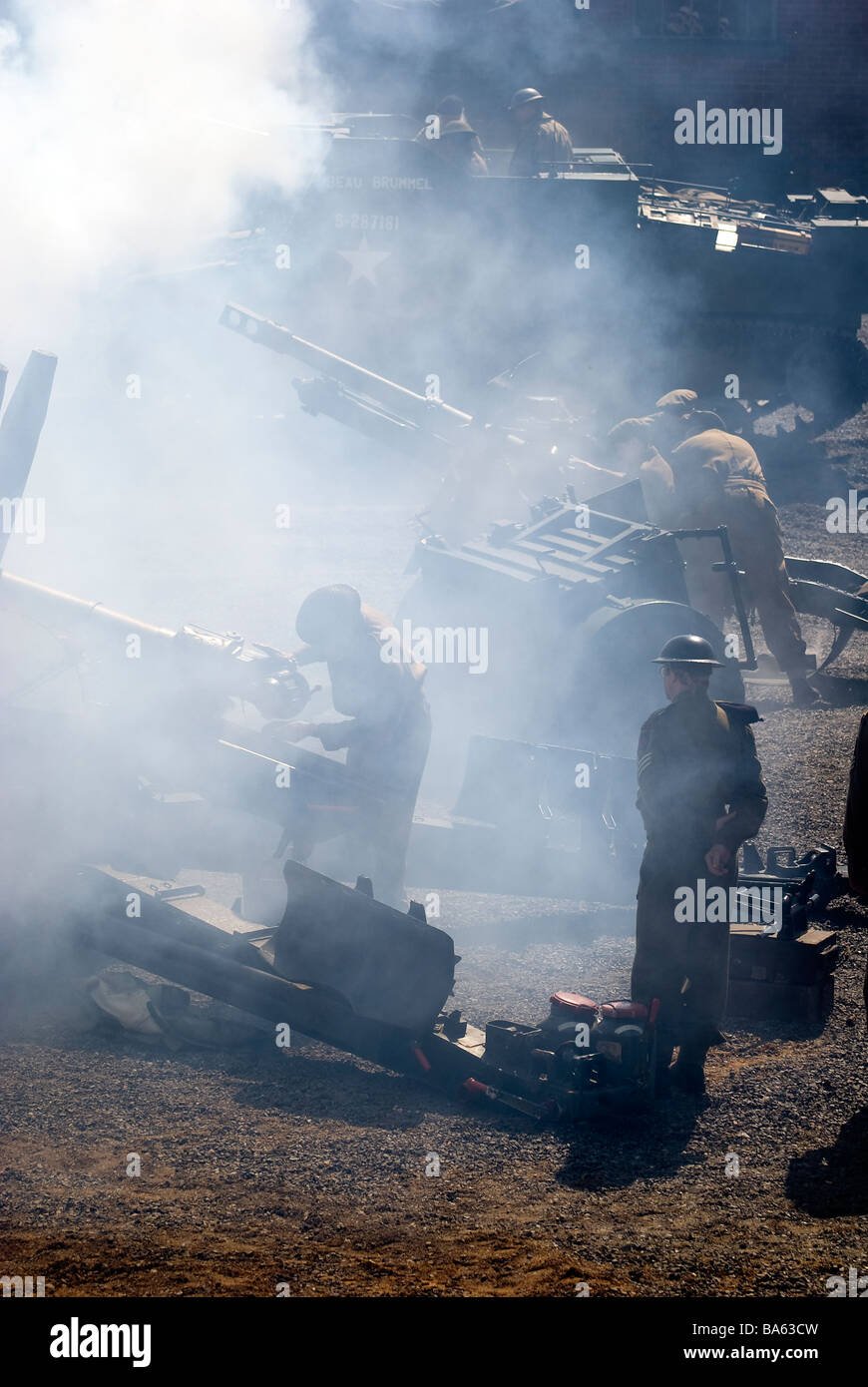 WW2 field guns being fired by crews with smoke blowing back across the ...
