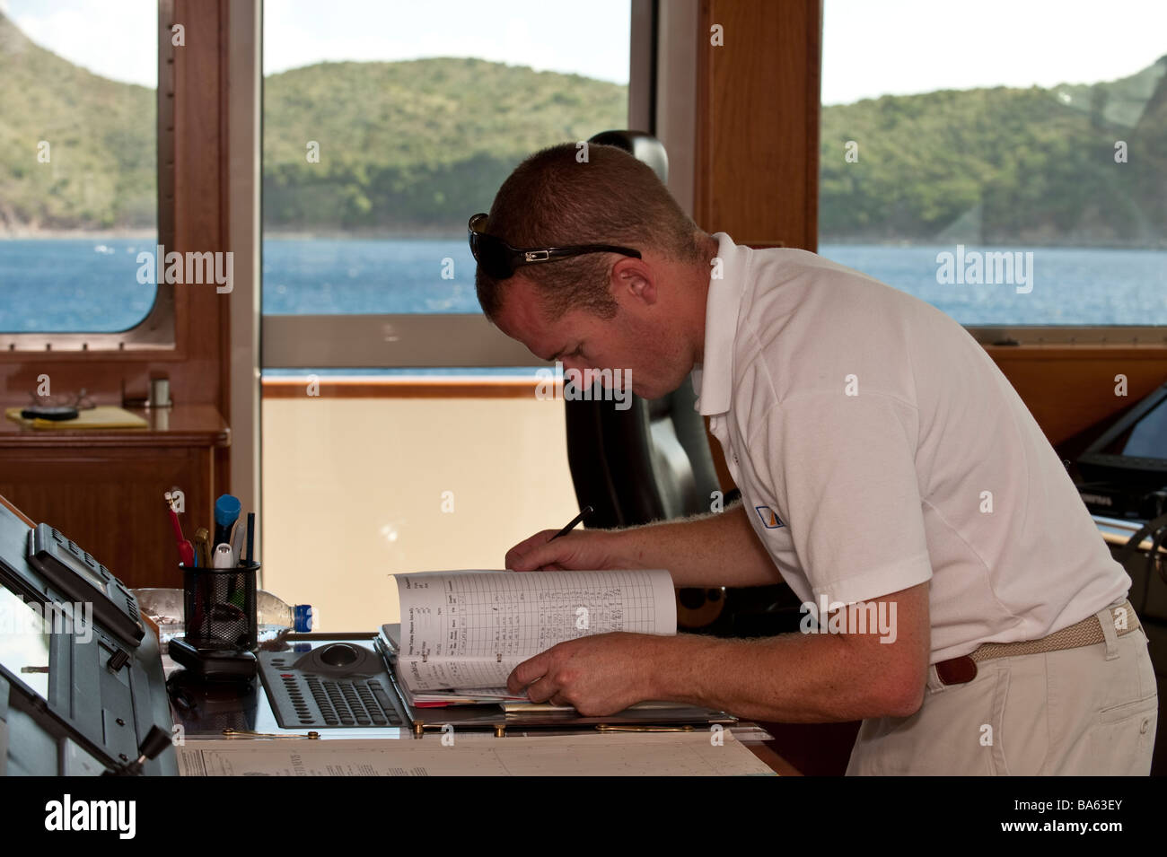 Chief Officer writing up the log book at the chart table aboard ...