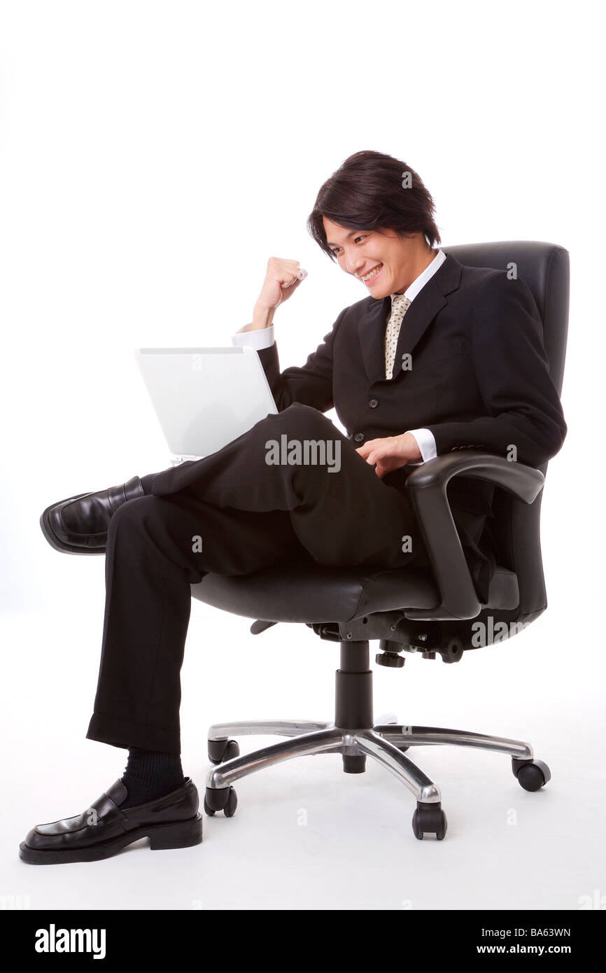 Businessman sitting with laptop on thigh smiling Stock Photo - Alamy