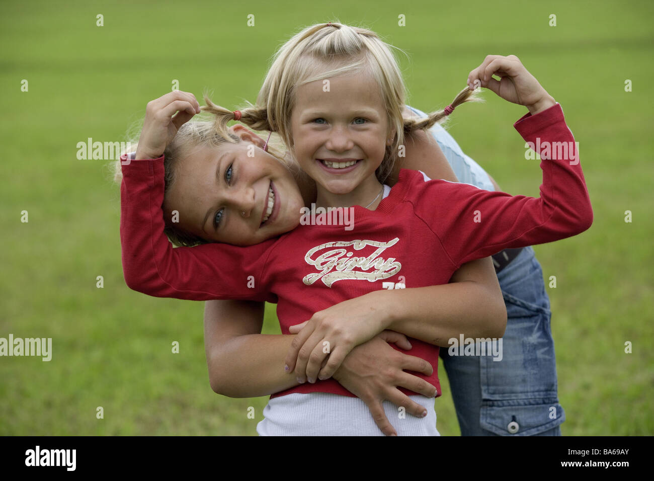 Sisters cheerfully embrace gesture braids semi-portrait people two ...