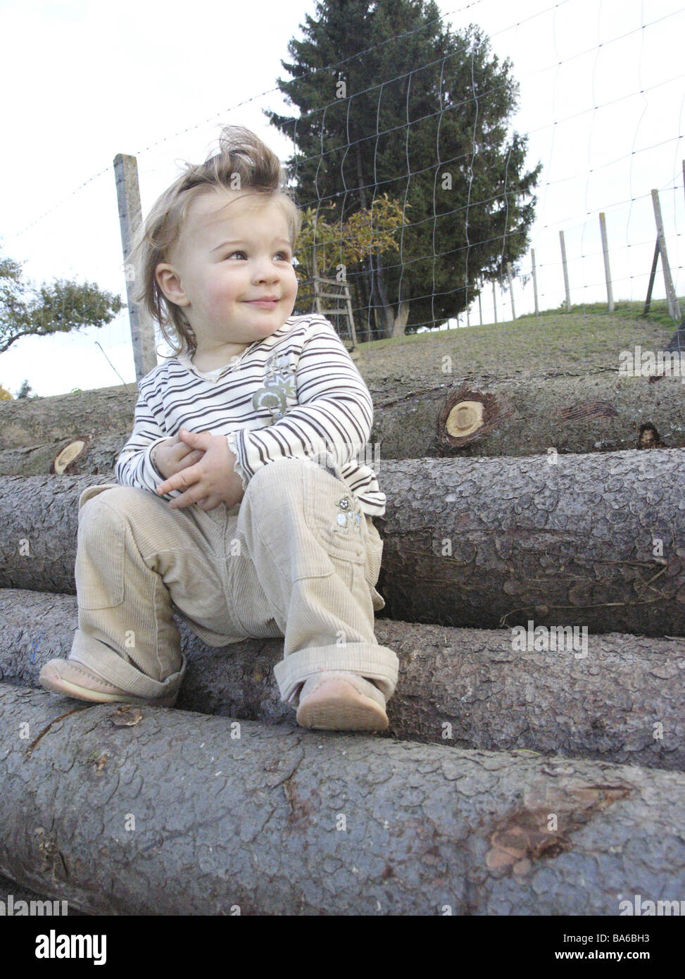 Tree-trunks stacked toddler sits smiles series people child girls 2-5 ...
