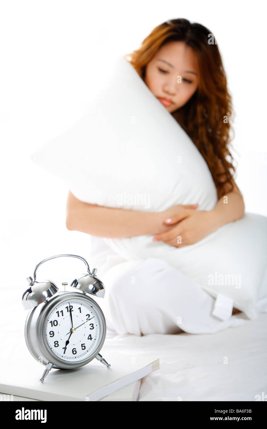 Woman in bed looking at alarm clock Stock Photo - Alamy