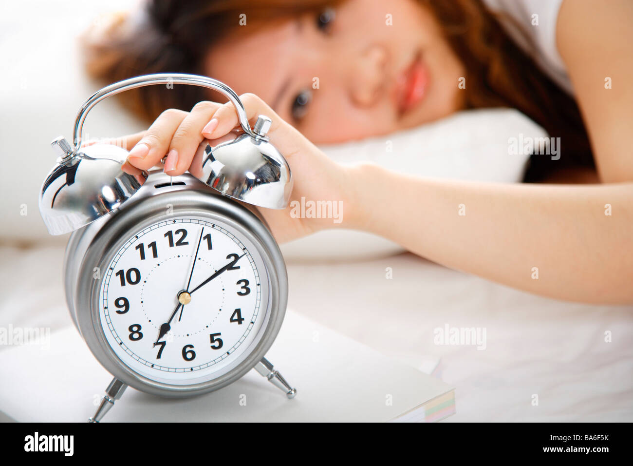 Woman putting off alarm clock Stock Photo - Alamy