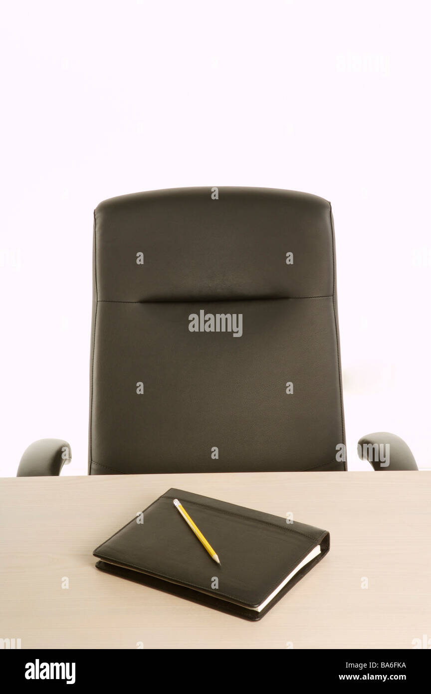 Notebook and pencil on desk with chair Stock Photo - Alamy