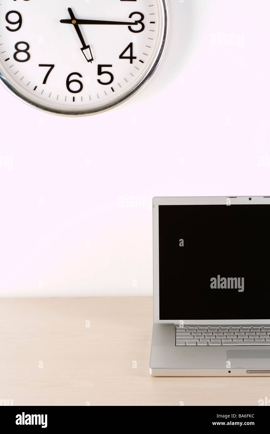 Laptop on conference table and clock on wall Stock Photo - Alamy