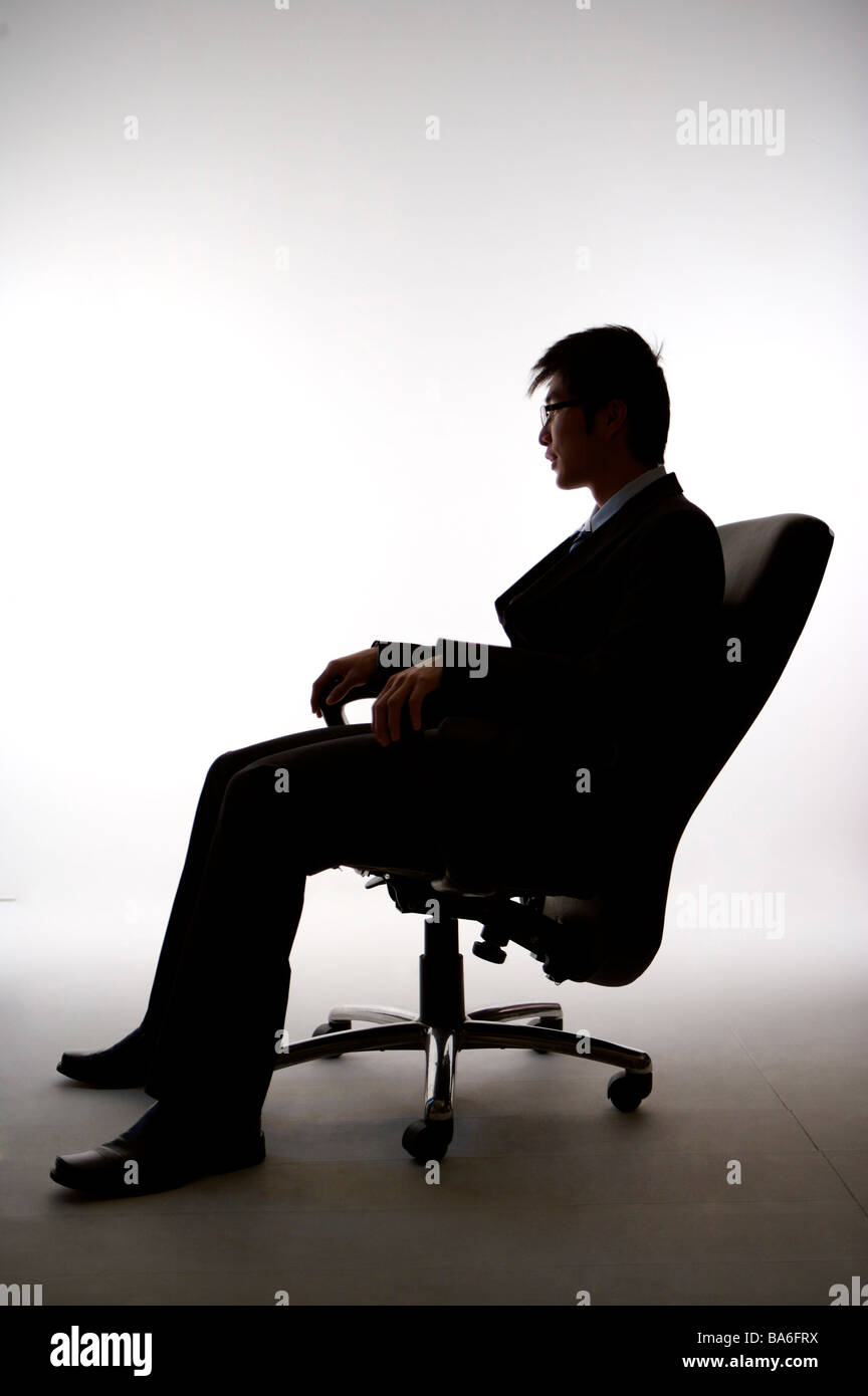 Businessman sitting on chair side view Stock Photo - Alamy
